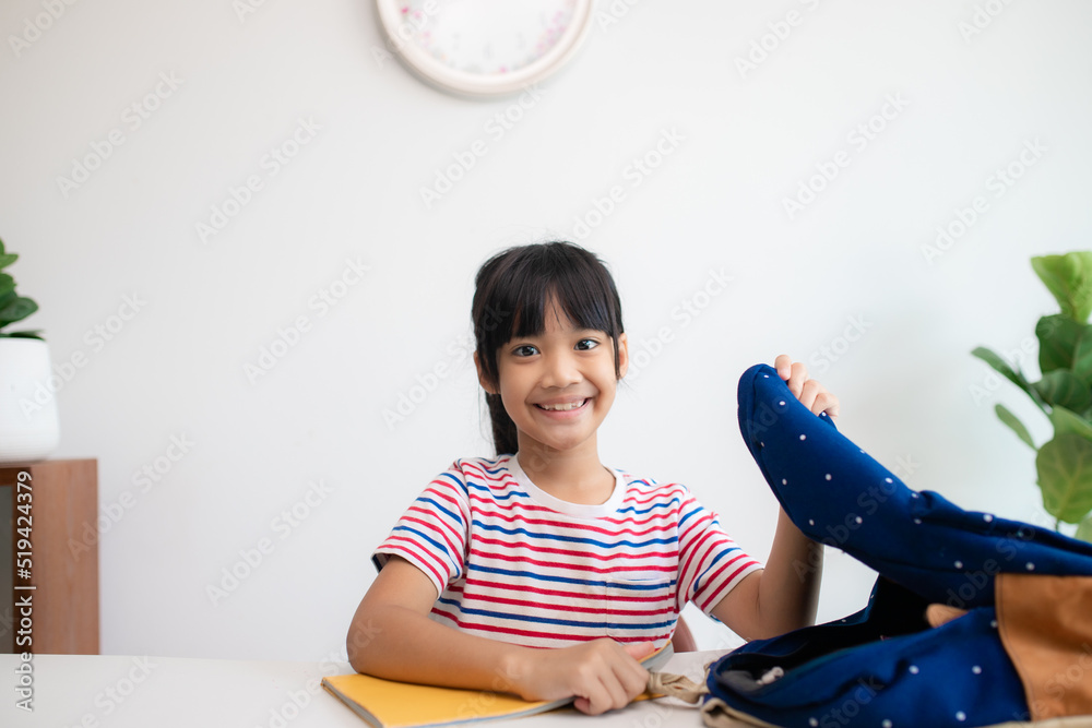 Asian cute primary school girls packing their school bags, preparing ...