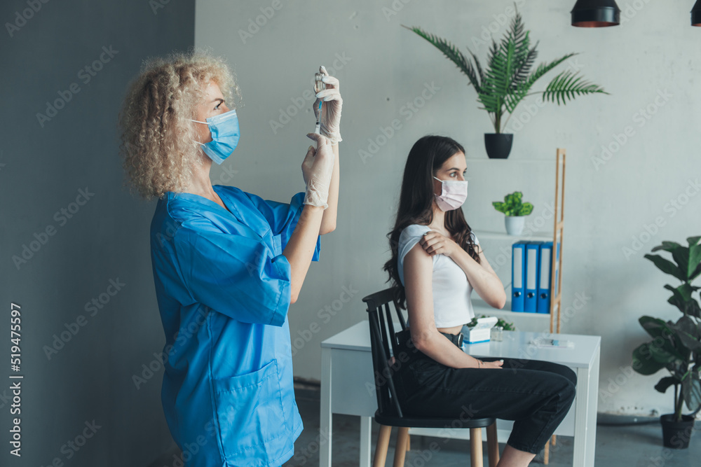 Nurse drawing medication out of vial before giving injection to patient ...