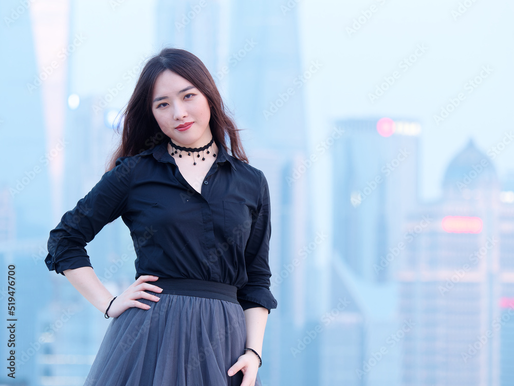 Beautiful young Chinese woman in black posing on top of mansion roof ...