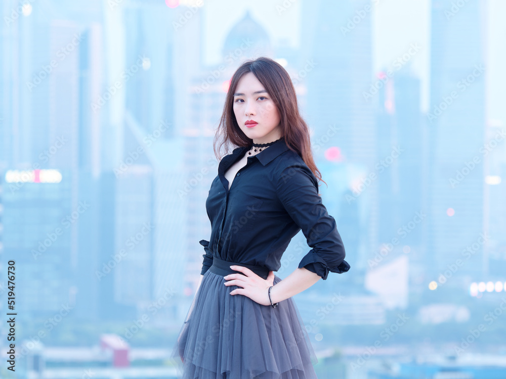 Beautiful young Chinese woman in black posing on top of mansion roof ...