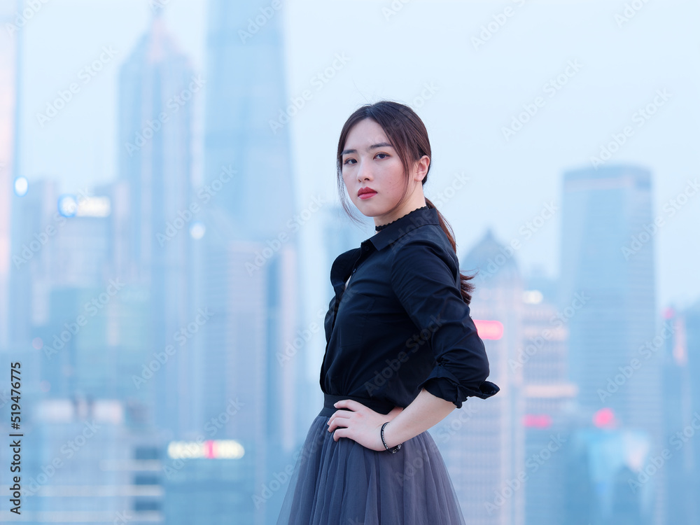 Beautiful young Chinese woman in black posing on top of mansion roof ...