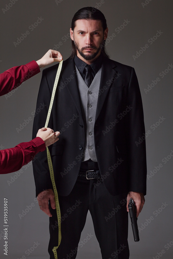 Tailor measuring arm length of bespoke suit. Studio portrait of bearded ...