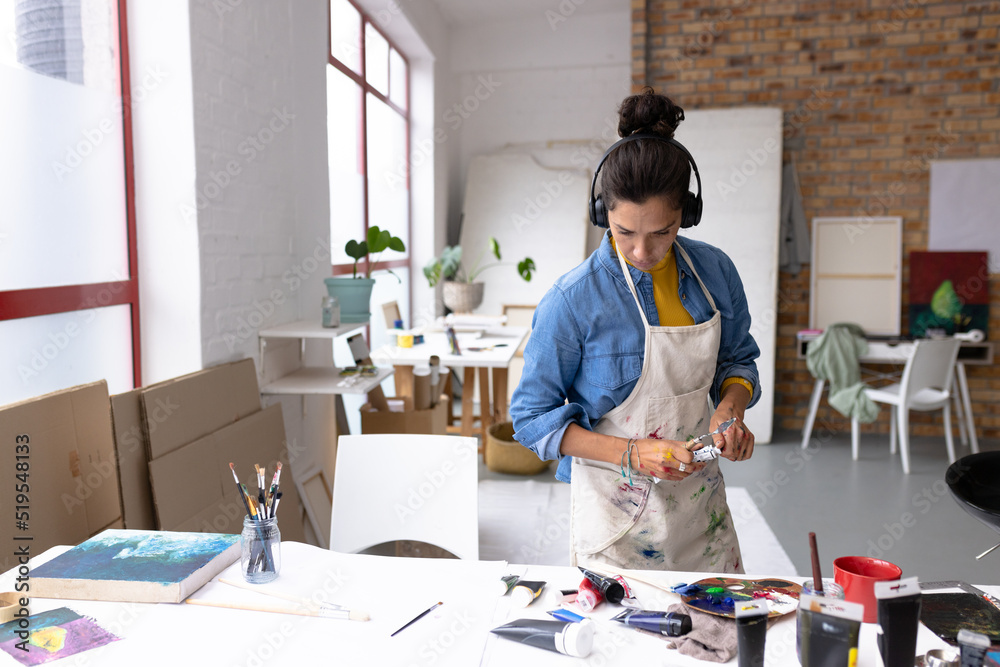 Image of back view of biracial female artist in headphones working on ...