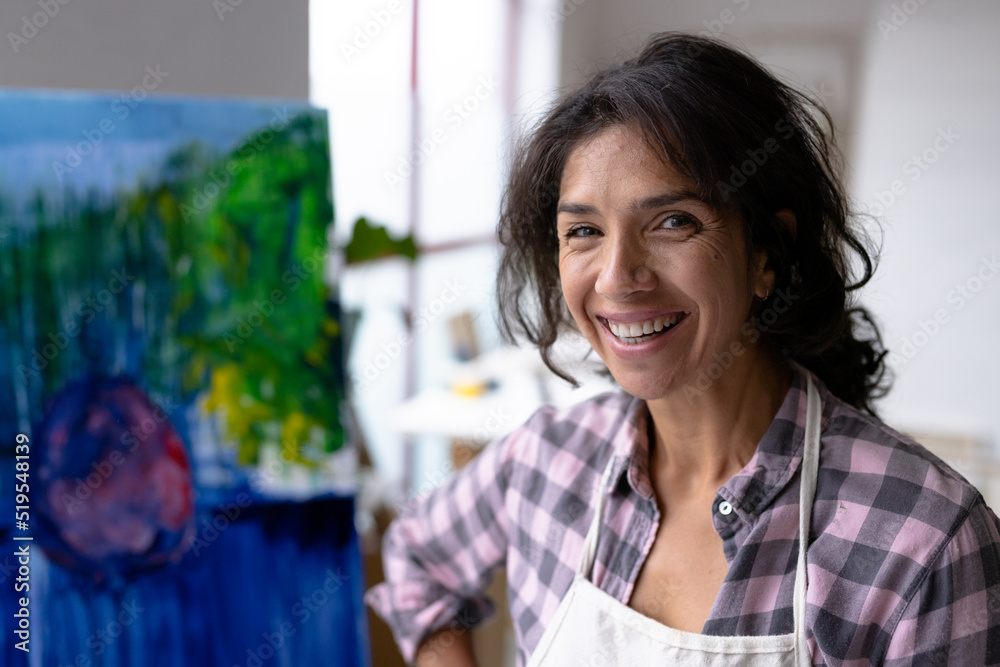 Image of happy biracial female artist working on new painting in studio ...