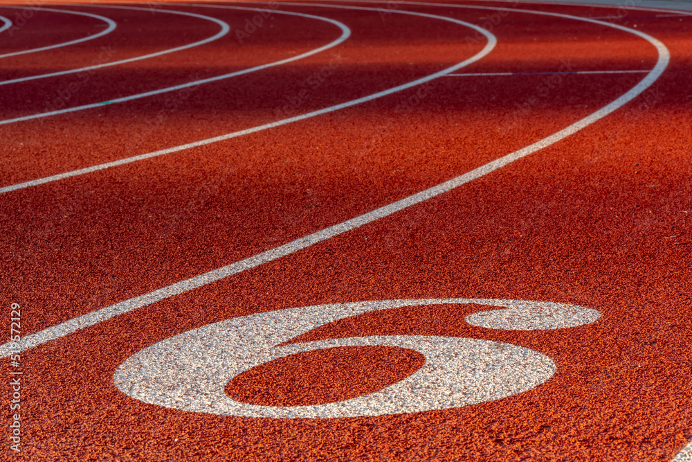 Close up lane number 6 on a new red running track with white lane lines ...