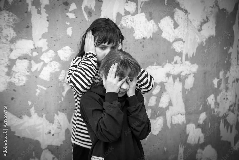 Two children at concrete wall scared and cover their ears with their ...