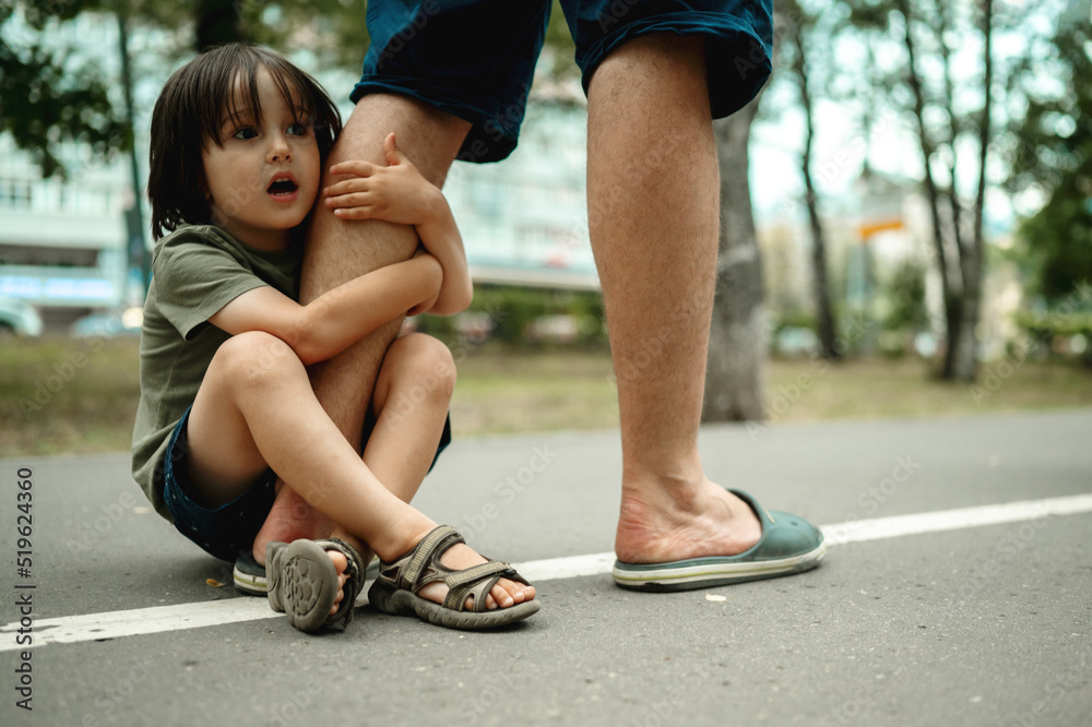 Dad and son are walking in the park, the child is hanging on his father ...