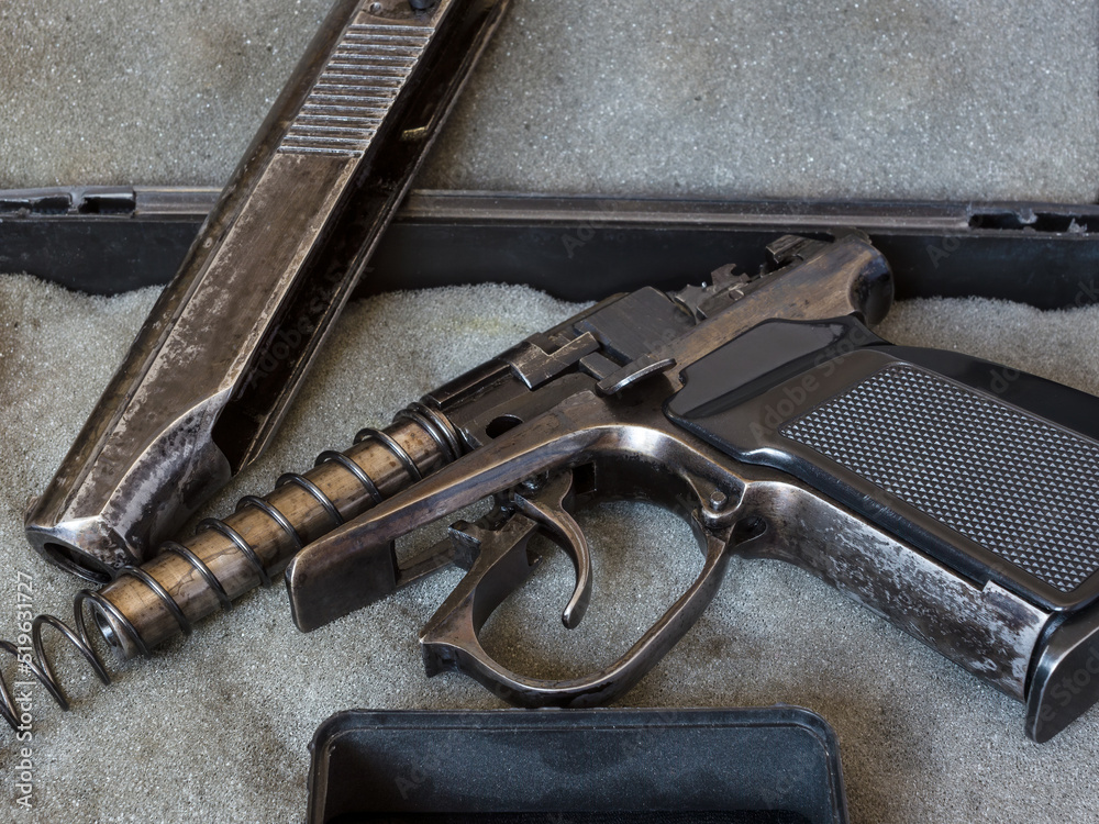 Partially disassembled old pistol, with the bolt removed, lying in a ...