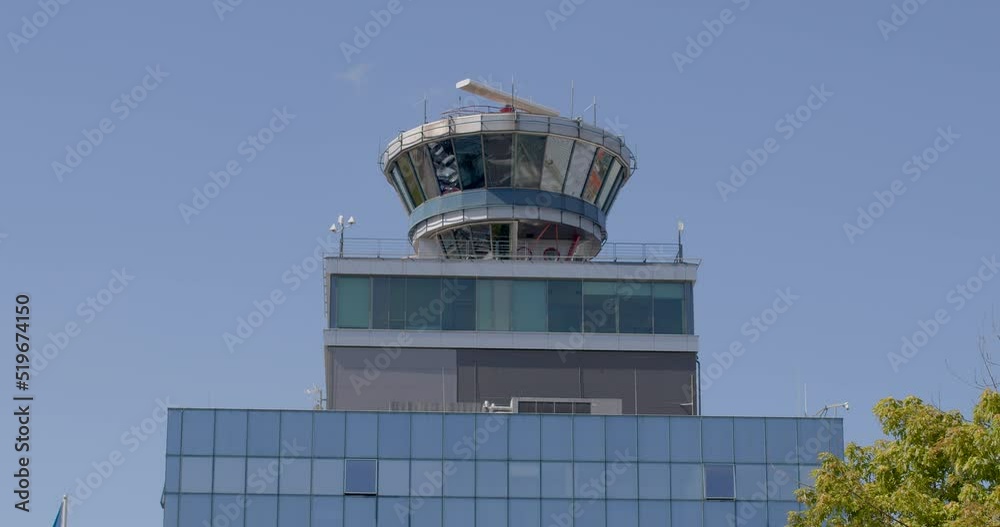 Facade of the glass building of the airport tower. A radar is spinning ...