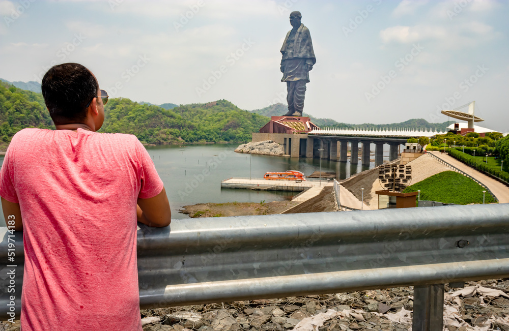 man looking at the statue of unity with bright dramatic sky at day from ...