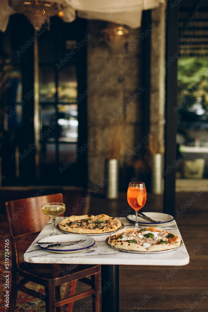 table setting in a pizzeria. two Italian pizzas with burnt sides and ...