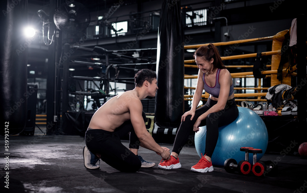 Young fitness woman and trainer are couple lover ,he take care to tying ...