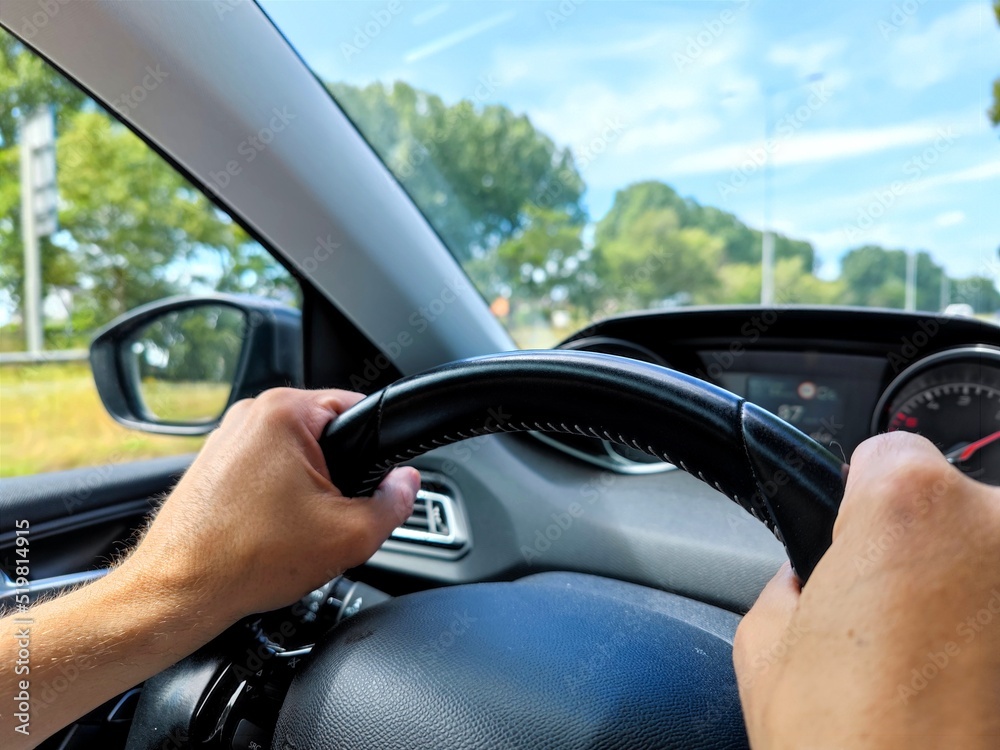 White men hands control a car steering wheel while driving on the road ...