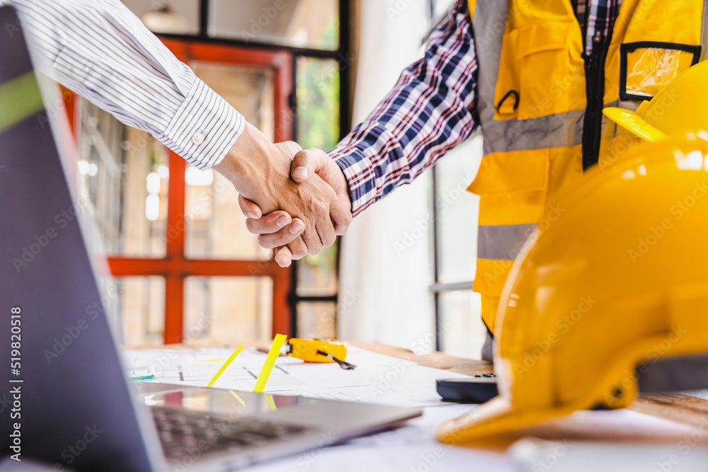Architects and engineers, construction workers shake hands while ...