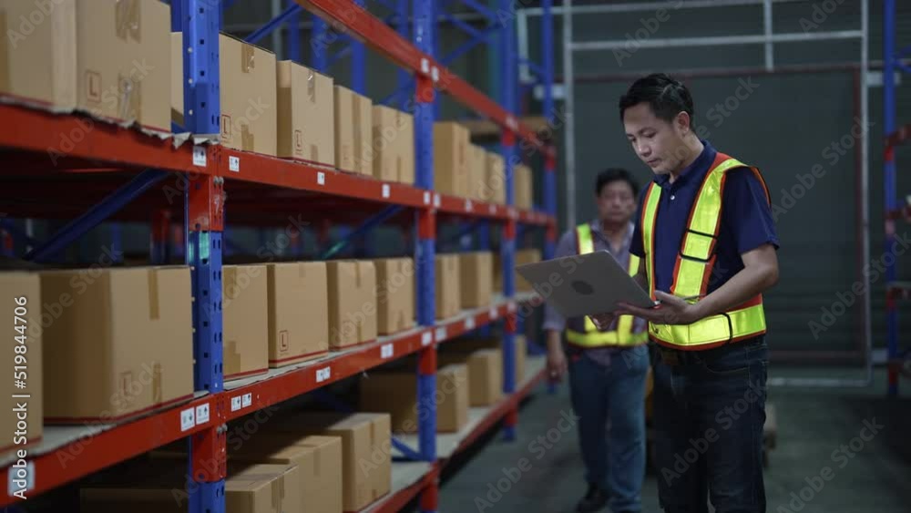 In the warehouse storage area supervior using laptop to check the ...