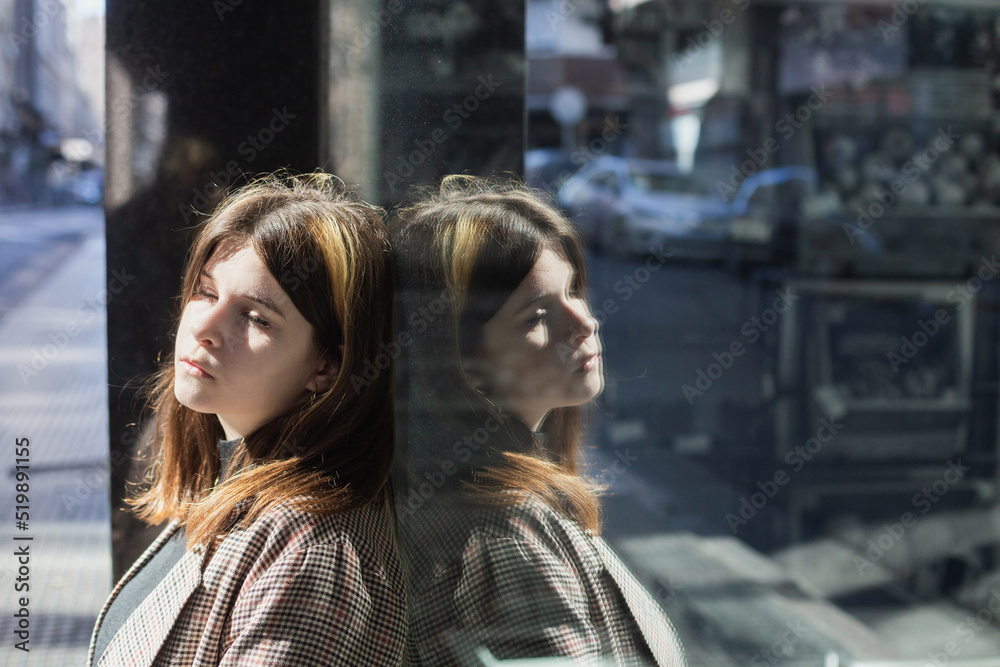 The girl sits at a transparent window and is reflected in it. Stock ...