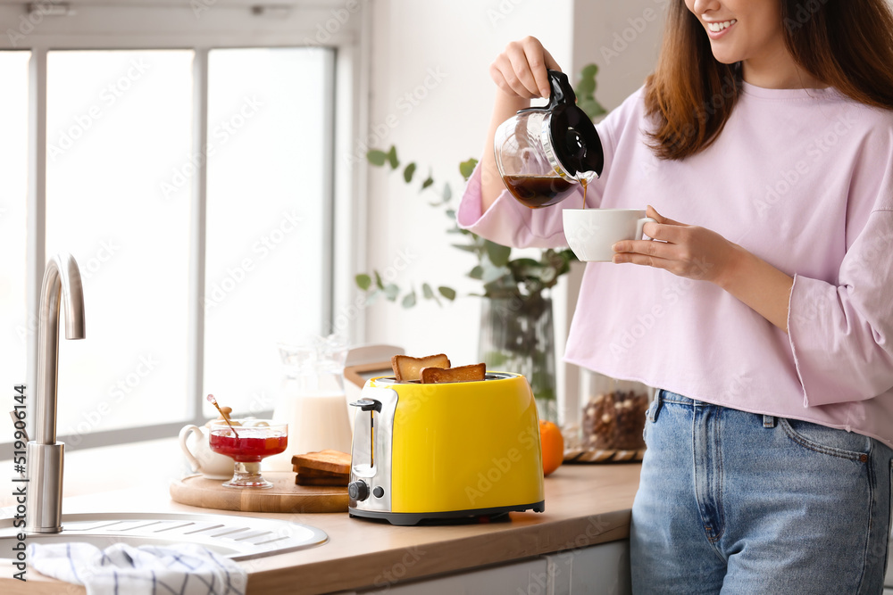 Beautiful young Asian woman drinking coffee and making tasty toasts in ...