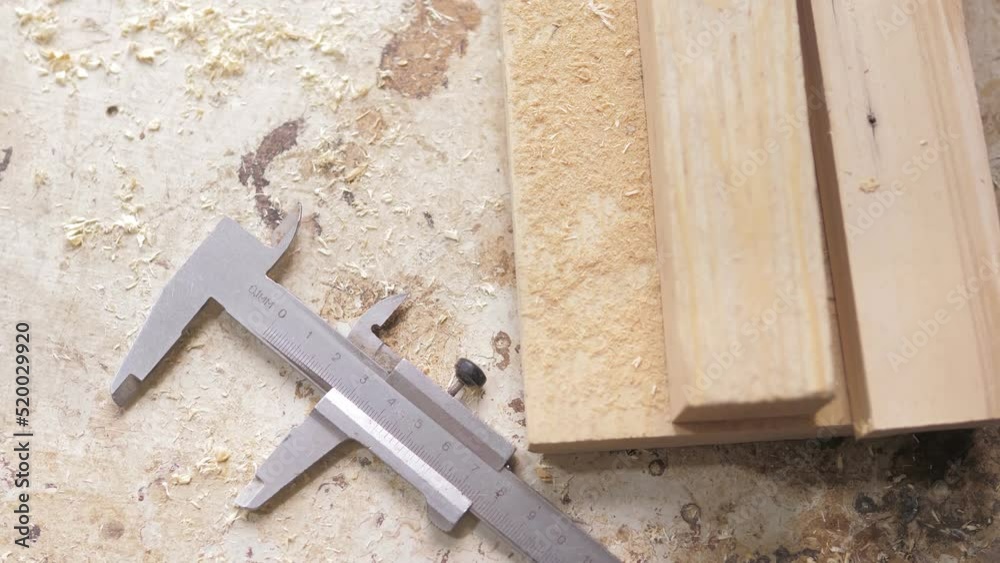 The caliper is lying on the carpenter's table near the wood and sawdust ...