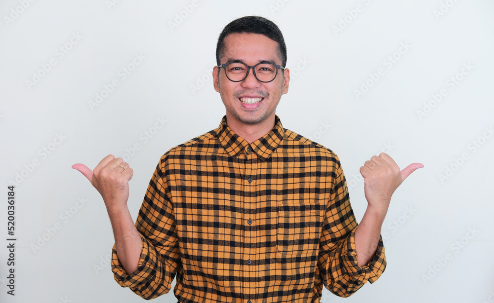 Adult Asian man smiling happy while pointing to the left and right with ...
