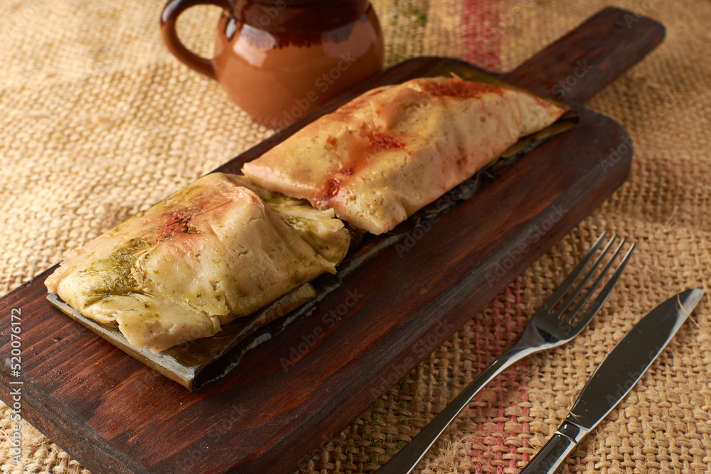Ranchero tamales with red and green sauce placed on their banana leaf ...