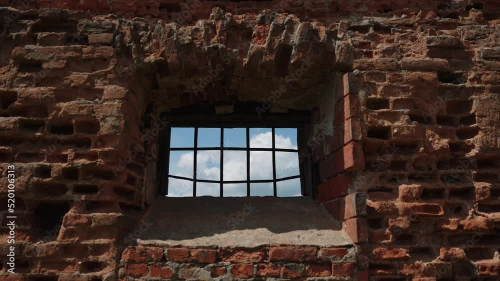 Old window with bent grid in recess of old ruined brick wall of ...