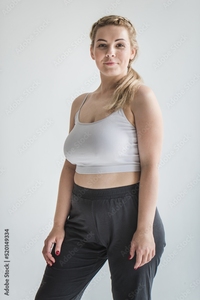 Young woman with overweight poses against a gray background in a crop ...