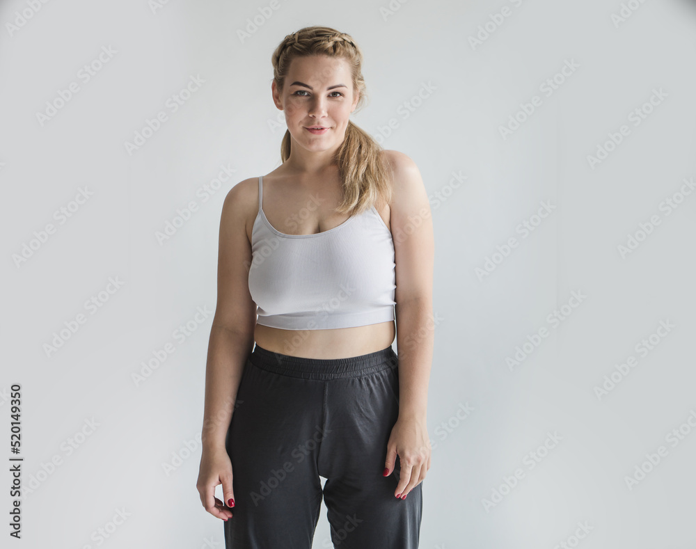 Young woman with overweight poses against a gray background in a crop ...