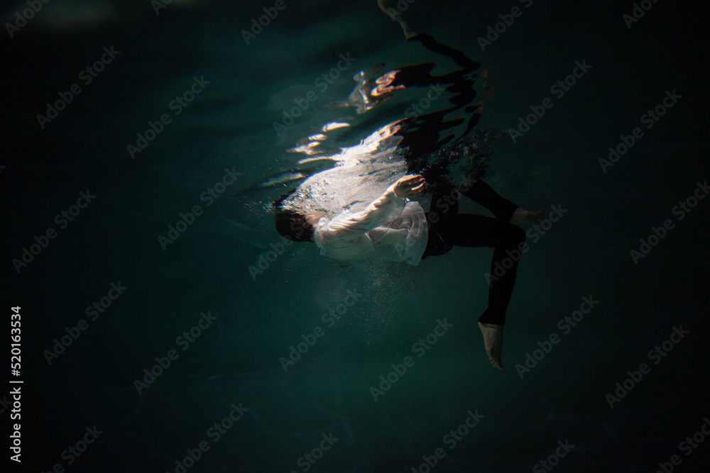 Beautiful underwater shooting, guy in white shirt and pants has fallen ...