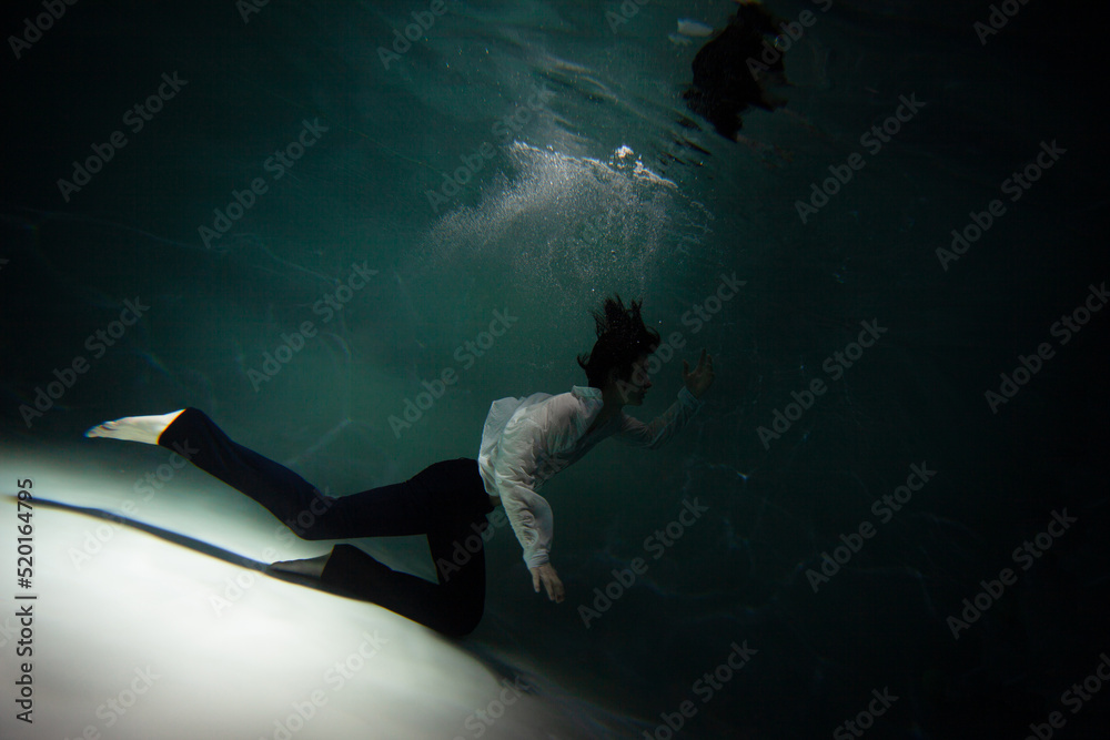 Beautiful underwater shooting, guy in white shirt and pants has fallen ...