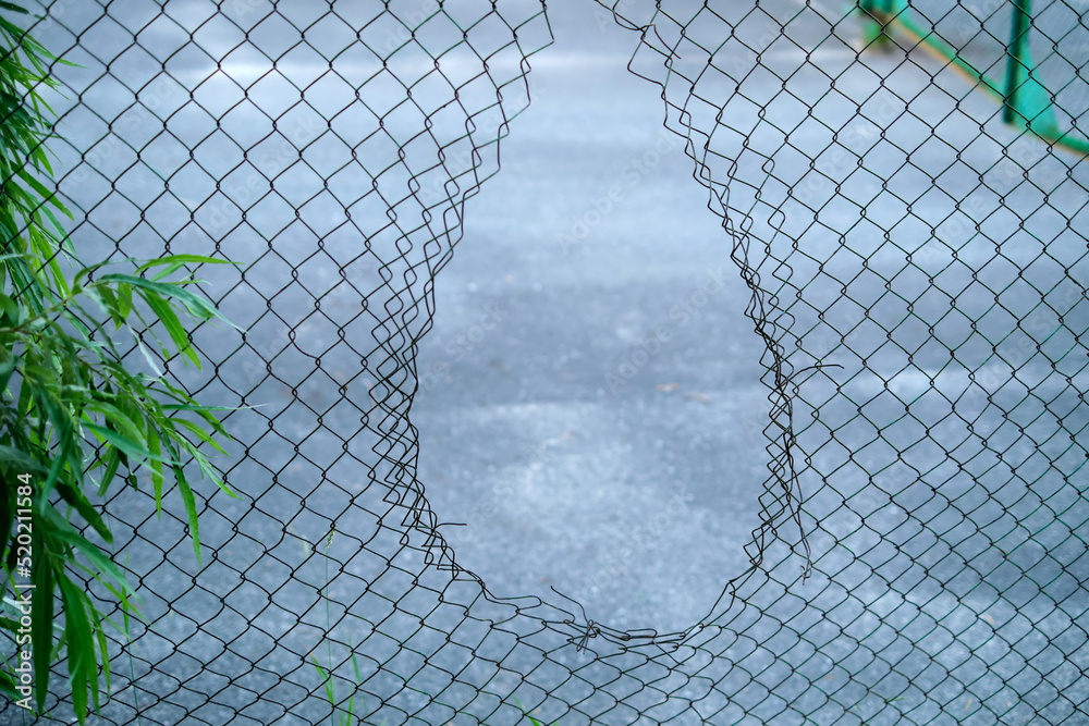 Hole in the fence. Mesh wire boundary. Steel mesh barrier fence. Chain ...