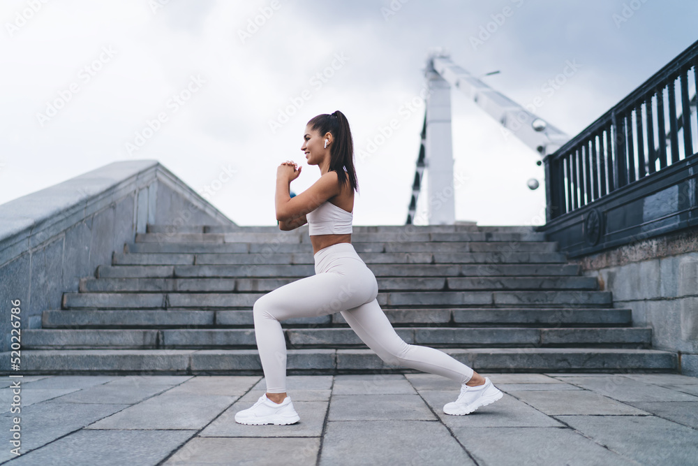Young happy woman makes deep forward lunges to pump the muscles of the ...