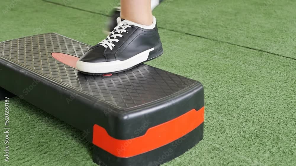 female legs in sports shoes perform stepping on an elevated step ...