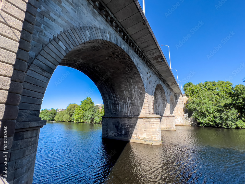 tall arched bridge over the Etienne river in Limoges, France with blue ...