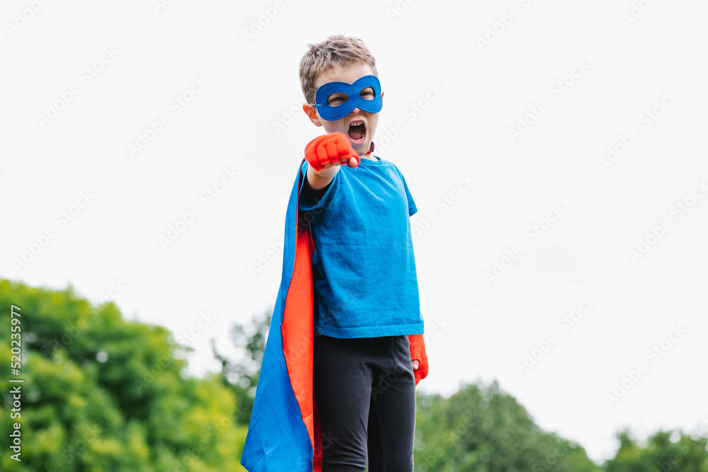 Excited boy in superhero costume in park Stock Photo | Adobe Stock