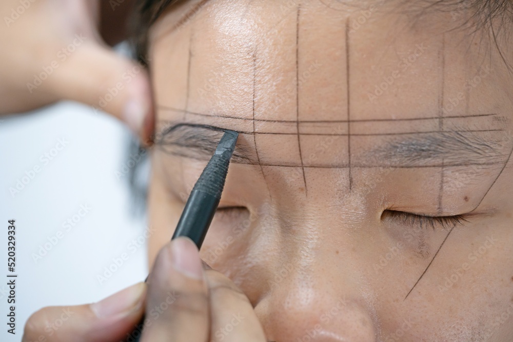 Foto de The process of shaping eyebrows by a beauty master with a thread for a young asian lady ...