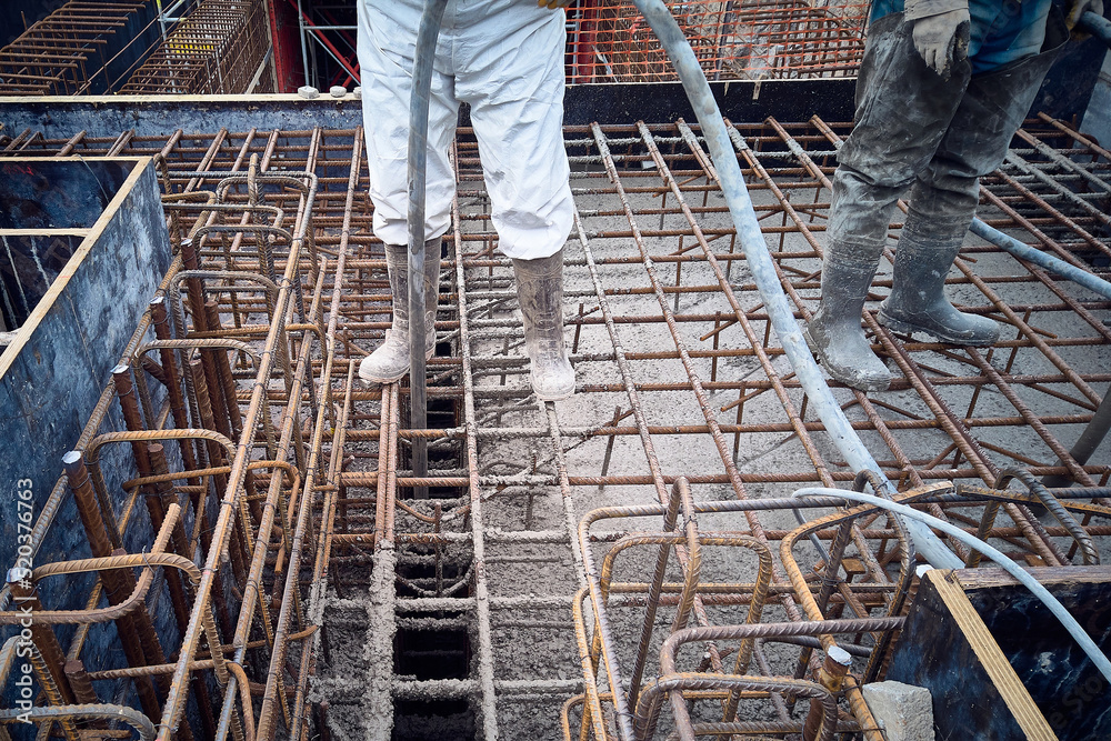 Construction workers dressed in protective workwear use concrete ...