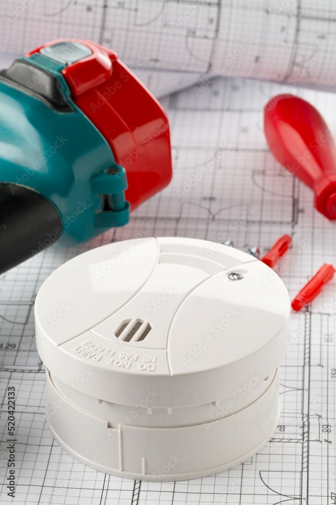 Smoke detector or fire alarm sensor on white architectural plans ...