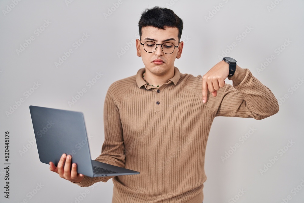 Non binary person using computer laptop pointing down looking sad and ...