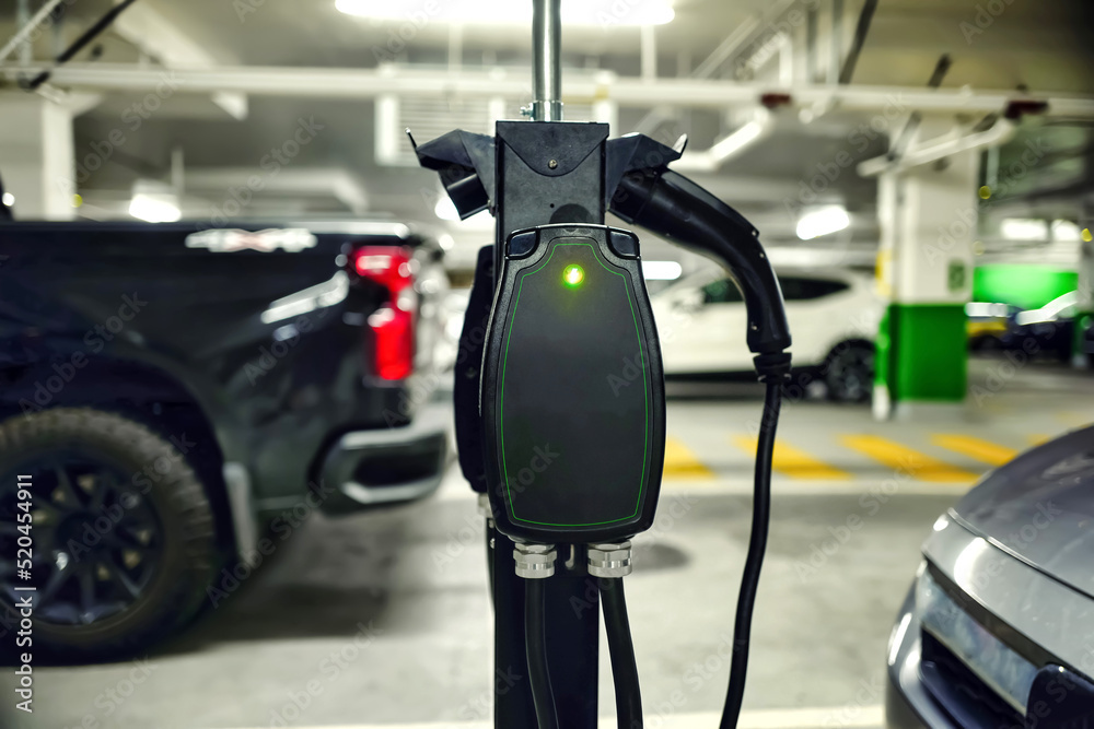 Modern EV charging station with cable and plug connected at condo ...