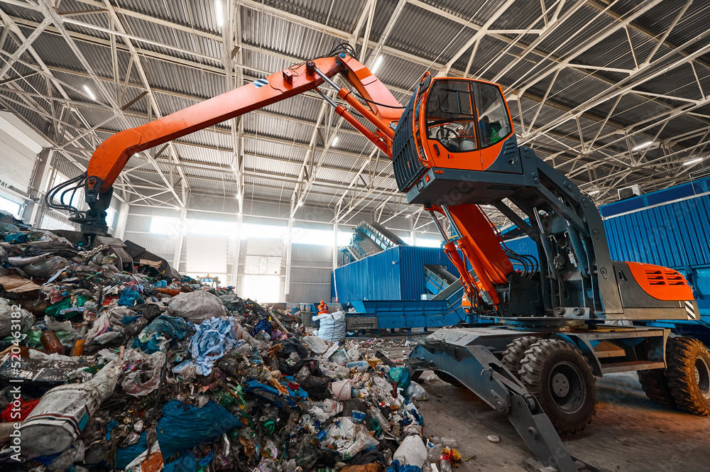 Excavator grabs trash in warehouse of waste processing plant Stock ...