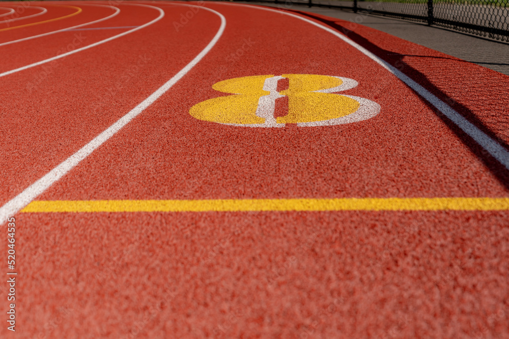 Close up lane number 8 on a new red running track with white lane lines ...