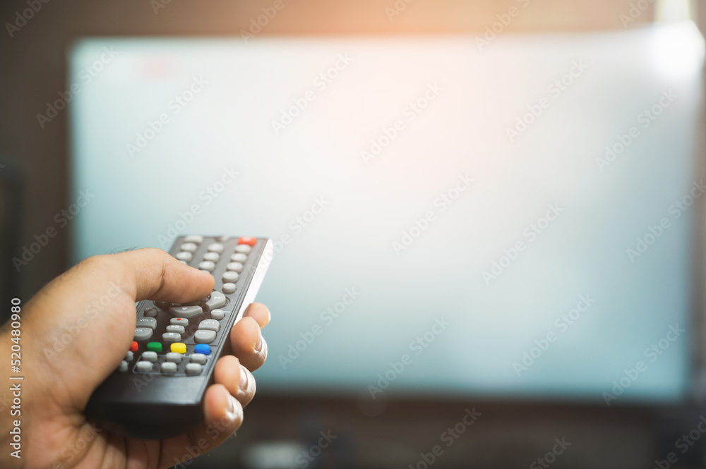 Young man holding television remote control. Hands pointing to tv ...