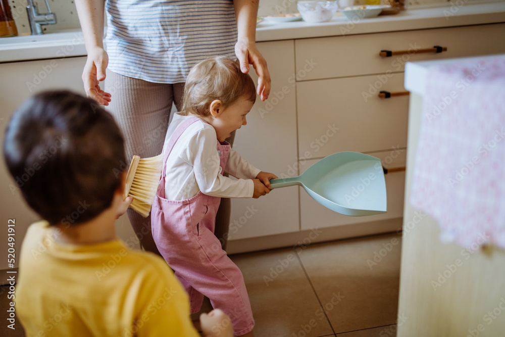 Little boy and girl helping to clean house using pan and brush as they ...