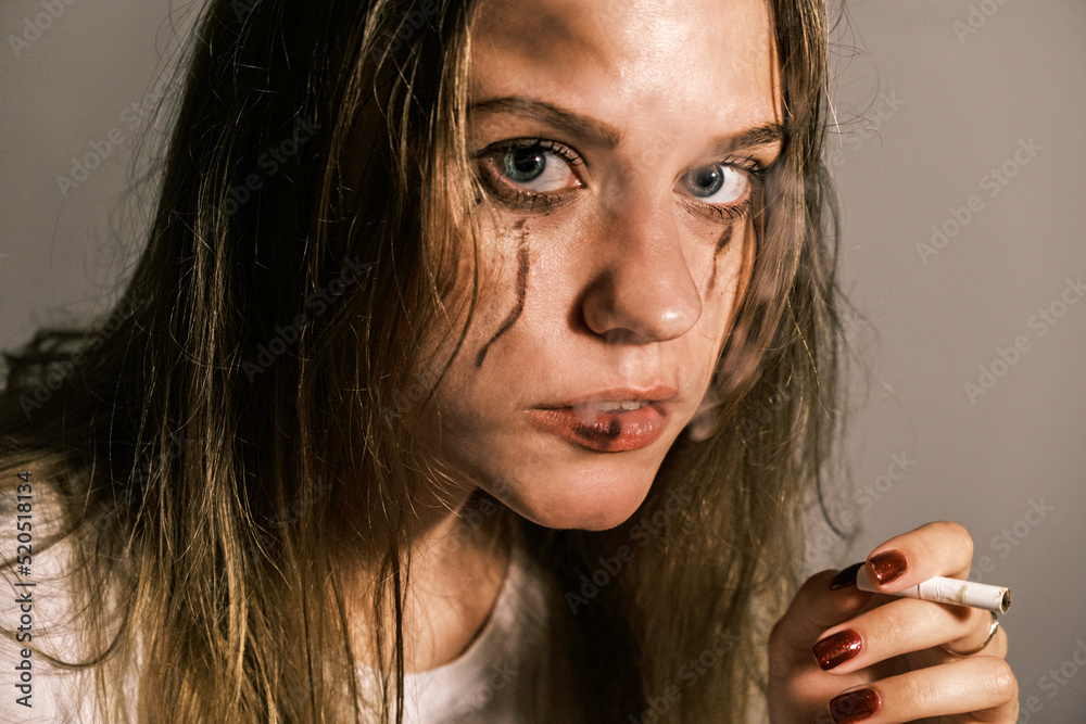 Crying young woman with cigarette in her hand and abrasions on her face ... Crying young woman with cigarette in her hand and abrasions on her face ...