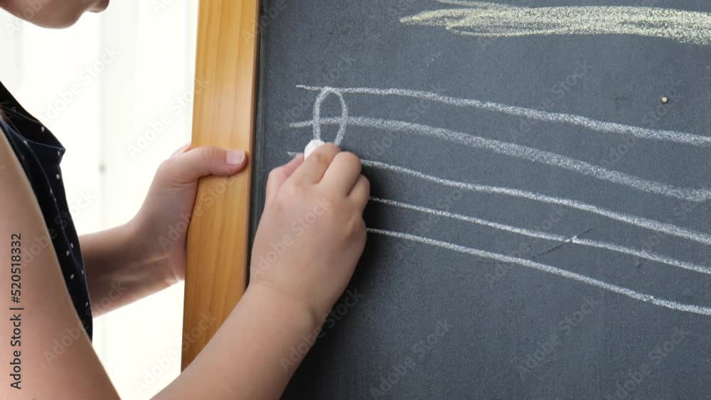 Child drawing a simple treble clef on a chalkboard, violin clef drawn ...