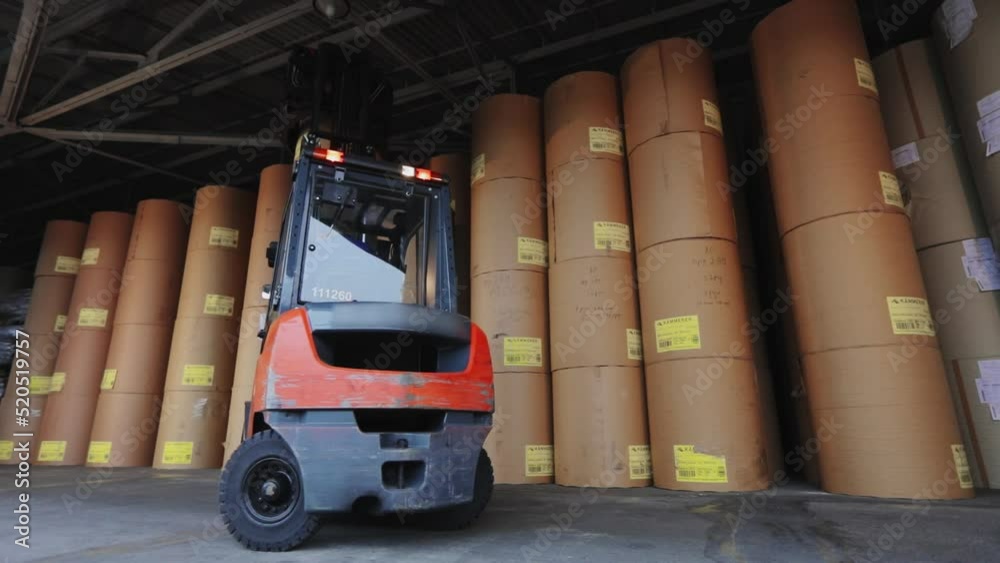 A forklift is carrying paper at the factory. Loader at the wallpaper ...