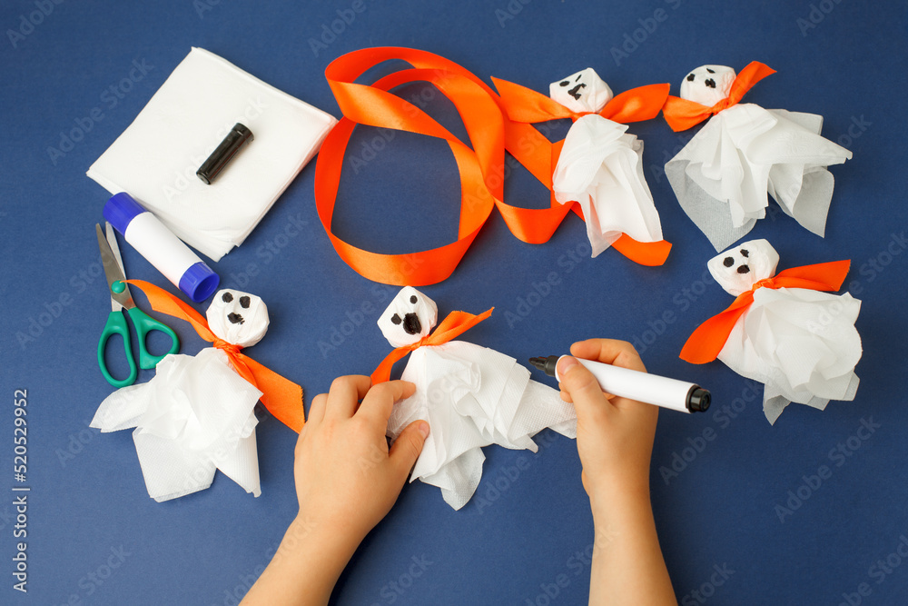 Boy makes Halloween toys ghost from white paper napkin. Creative DIY ...