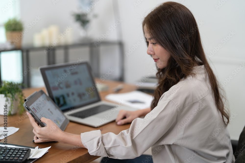 Beauful girl in the office using laptop computer and tablet surfing ...