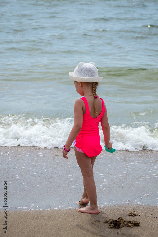 little girl in a pink swimsuit on the beach Stock Photo | Adobe Stock