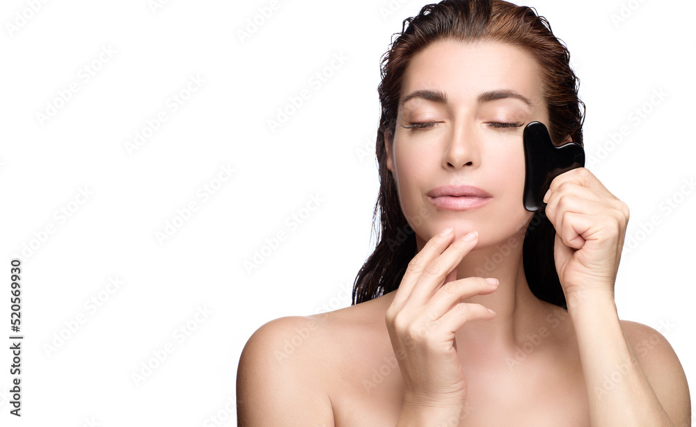 Serene woman using a Gua sha tool along side face. Beautiful female ...